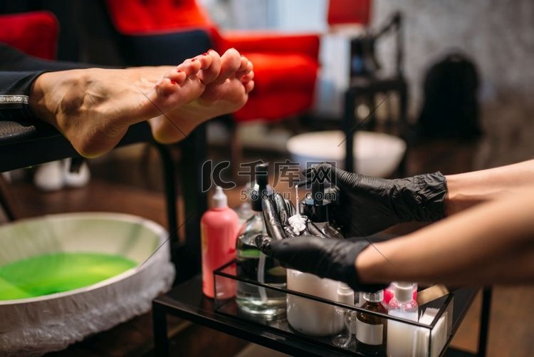 黑手套的修脚师在修脚浴后做足部按摩美容院的女性客户高清摄影大图 千库网
