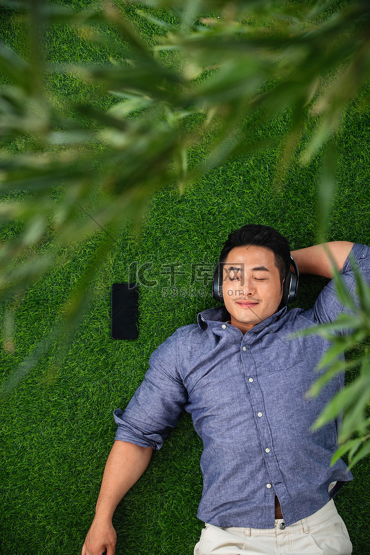 躺在草地上听音乐的青年男人高清摄影大图 千库网