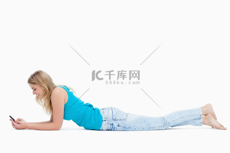 一个女人躺在地上用手机发短信高清摄影大图 千库网