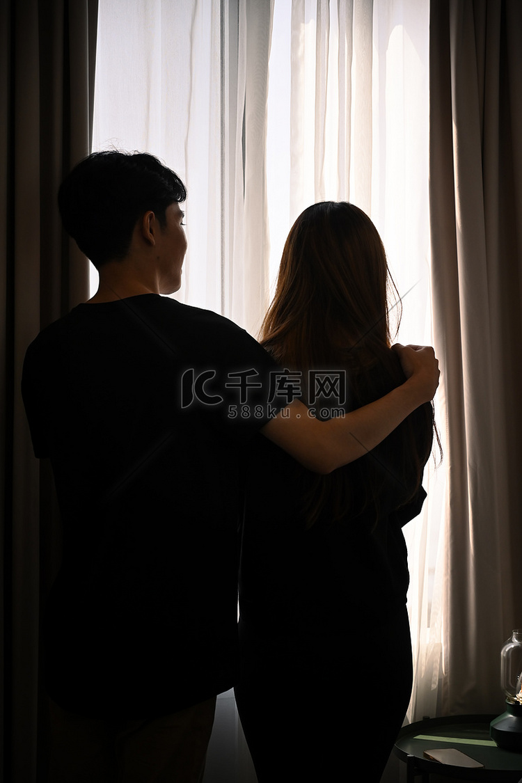 在家里窗户对面的客厅里一对年轻夫妇相拥而立的剪影高清摄影大图 千库网