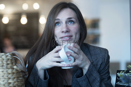 一名年轻女子一边在咖啡馆喝咖啡一边抬头看高清摄影大图 千库网