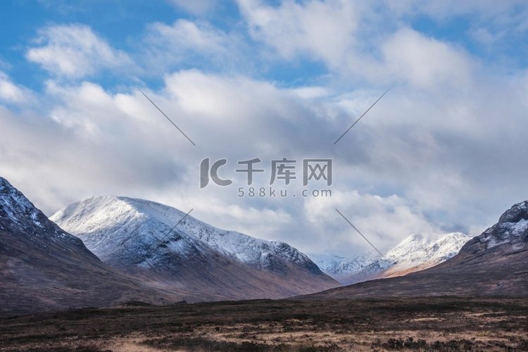 苏格兰迷失山谷令人惊叹的美丽冬季景观图像，白雪皑皑的 Buachaile Etive Baeg 沙地遥远的山脉和戏剧性的天空高清摄影大图-千库网