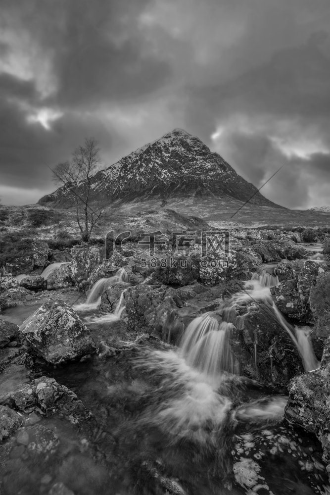 苏格兰高地 Stob Dearg Buachaille Etive Mor 标志性山峰的黑白壮丽的冬季日落景观，前景是著名的 Etive 河 ...
