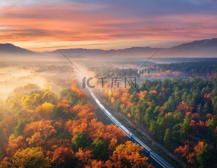 日落时雾中美丽森林中旅客列车的鸟瞰图。霞光天空高清摄影大图-千库网