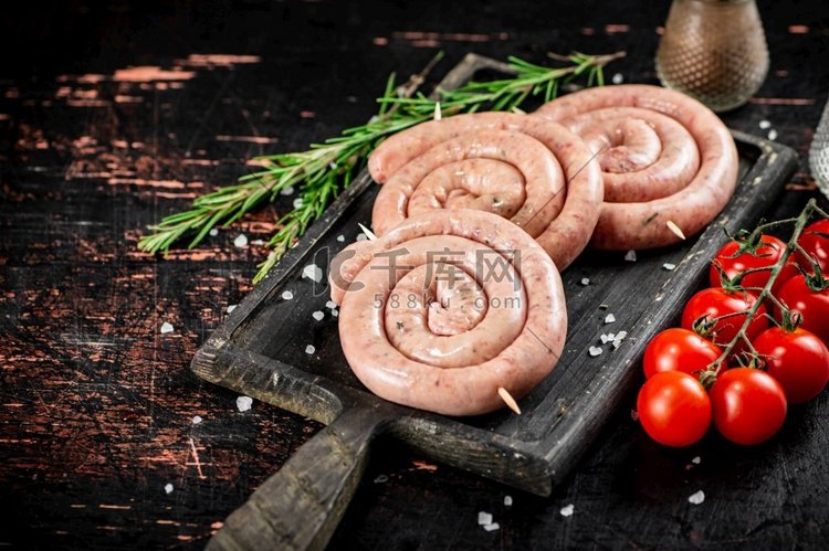 切菜板上的生香肠，上面放着迷迭香和西红柿。柿饼图钉高清摄影大图-千库网