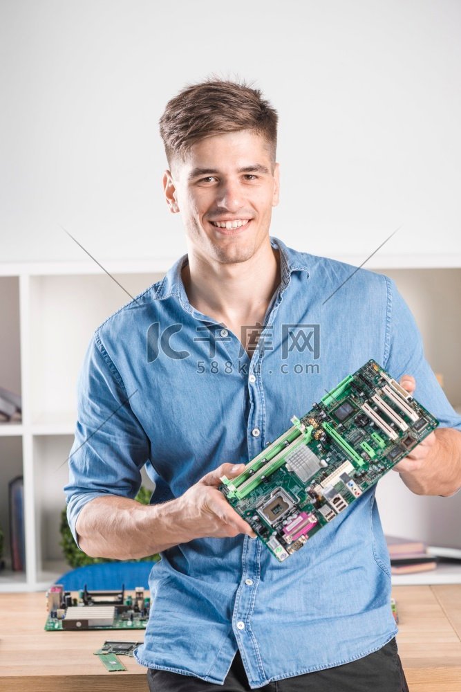拿着现代计算机主板的画象愉快的男性技术员高清摄影大图-千库网