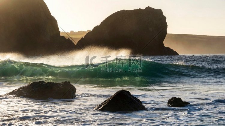 Kynance Cove Cornwall 的翡翠绿松石波浪冲击海岸和岩石的史诗景观图像，日出背景发光，风中喷水滴高清摄影大图-千库网