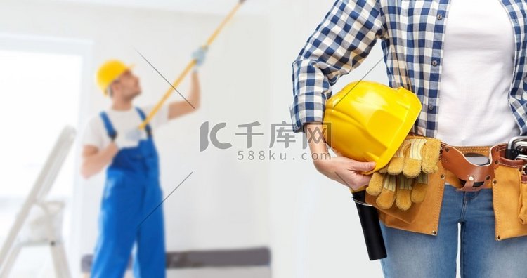 维修、施工和建筑概念-在背景上的绘画作品上，用头盔和腰带上的工作工具关闭女性或建筑商。高清摄影大图-千库网