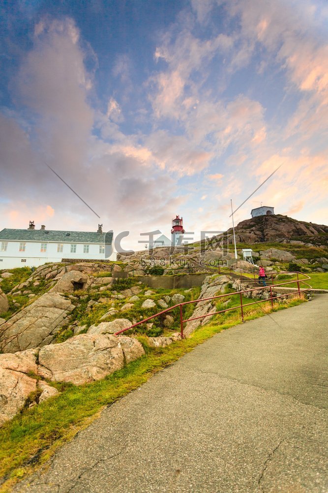 挪威南部 Lindesnes Fyr 灯塔岩石海岸边缘的旅游妇女和历史悠久的红白色灯塔。高清摄影大图-千库网