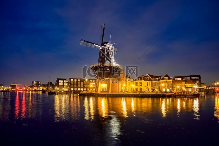 在暮色中照亮的 Spaarne 河上的哈莱姆地标风车 De Adriaan 的夜景。高清摄影大图-千库网