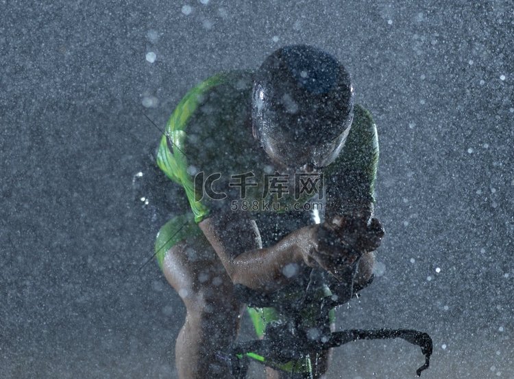 铁人三项运动员在恶劣天气和下雨的夜间骑专业赛车高清摄影大图-千库网