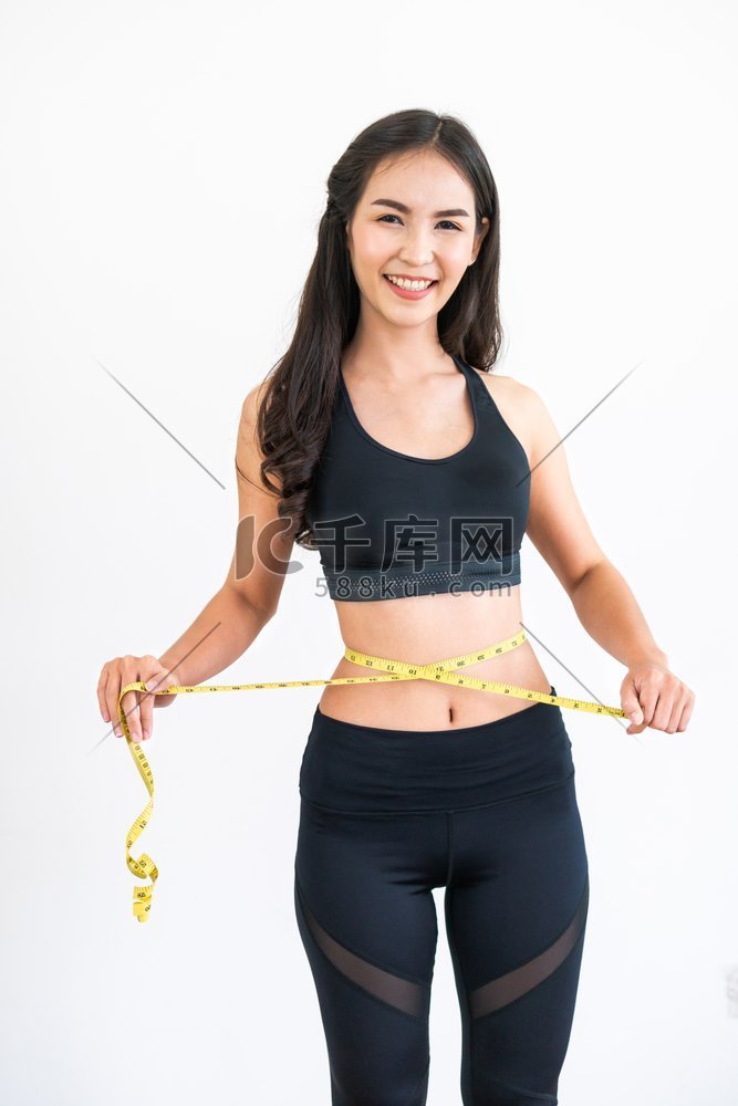 测量她的腰围和躯干的苗条身材的女人的特写镜头。高清摄影大图-千库网