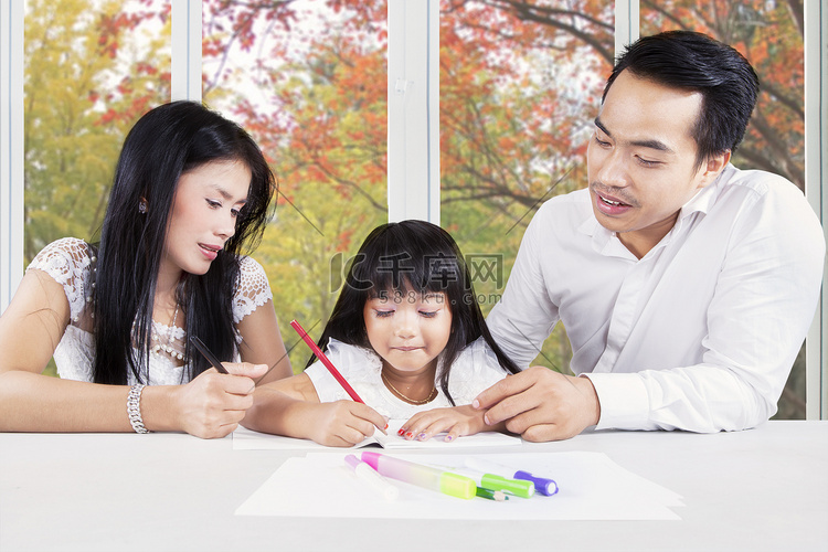Creative child studying with parents at home高清摄影大图-千库网