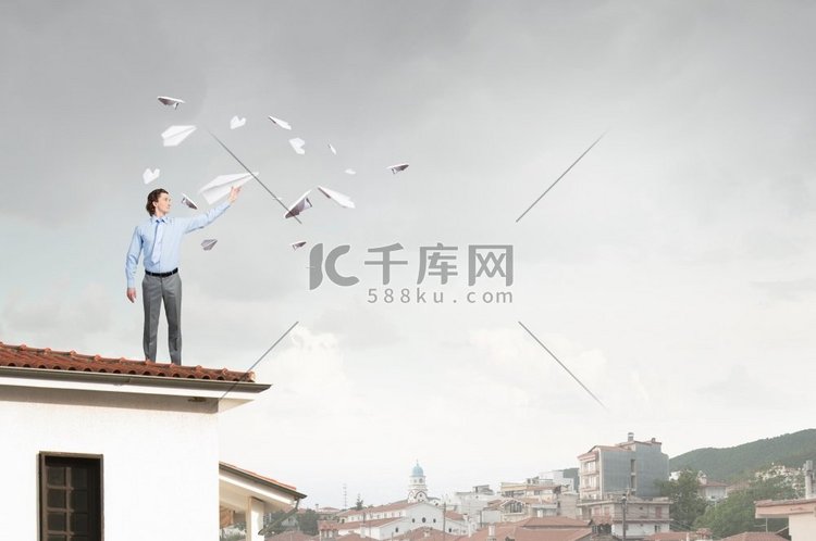 手里拿着纸飞机在户外的年轻商人高清摄影大图-千库网