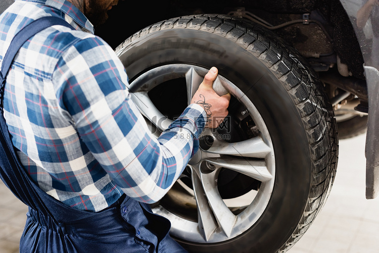 partial view of technician fixing car wheel in workshop高清摄影大图-千库网