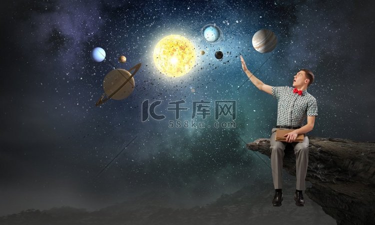 年轻人带着一本探索太阳系行星的书。太空之谜高清摄影大图-千库网