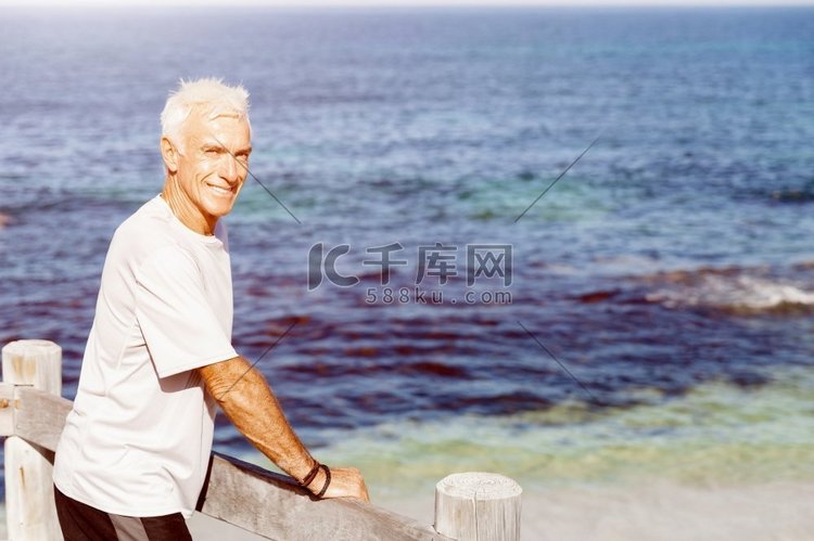 穿着运动服站在海滩上的男人。一名男子穿着运动服站在海滩上，看起来健康而快乐高清摄影大图-千库网