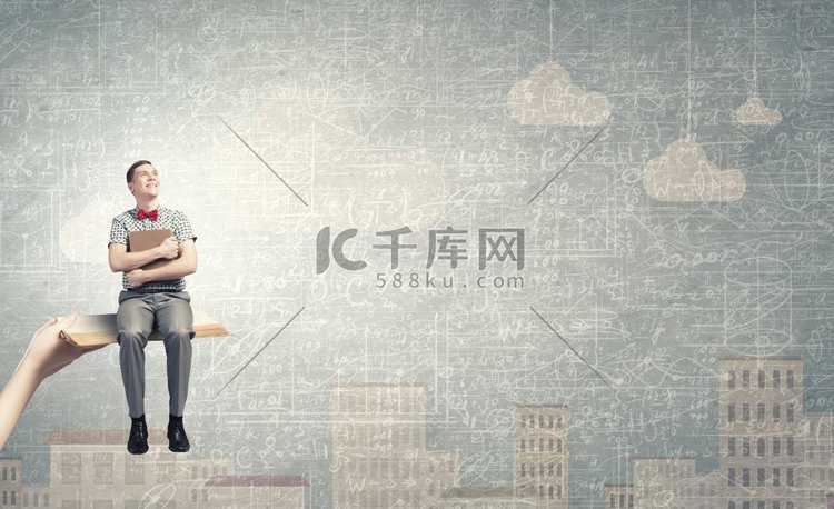 我的爱好是读书。年轻的男学生手里拿着书坐着高清摄影大图-千库网