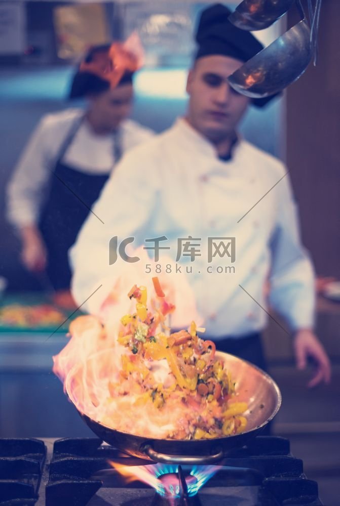 厨师烹饪和做flambe在餐厅厨房的食物。厨师在食物上做火焰高清摄影大图-千库网