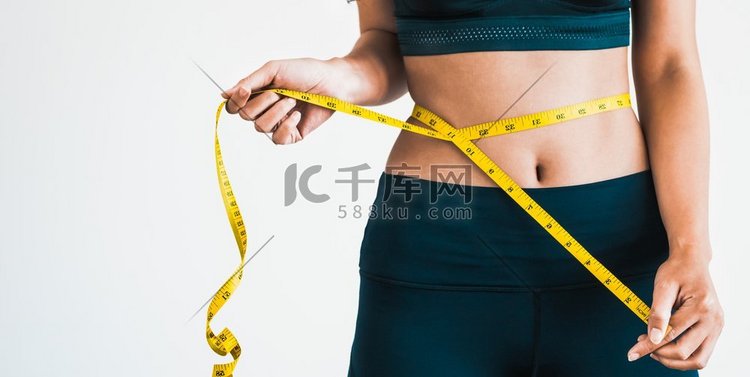 测量她的腰围和躯干的苗条身材的女人的特写镜头。量尺呼啦圈高清摄影大图-千库网