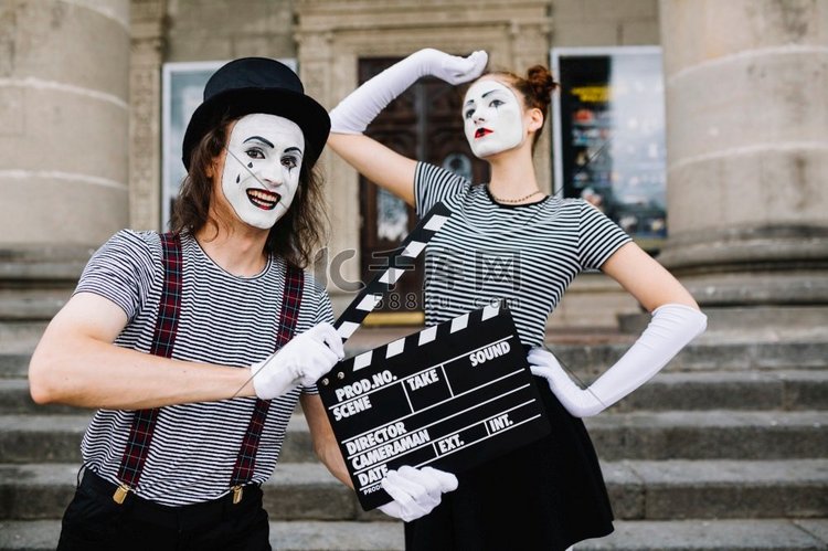 快乐的男性 mime 拿着 clapperboard 前面摆姿势的女性 mime高清摄影大图-千库网