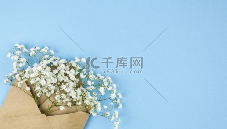 棕色信封与小白色的gypsophila花安排角落蓝色背景 高清摄影大图-千库网