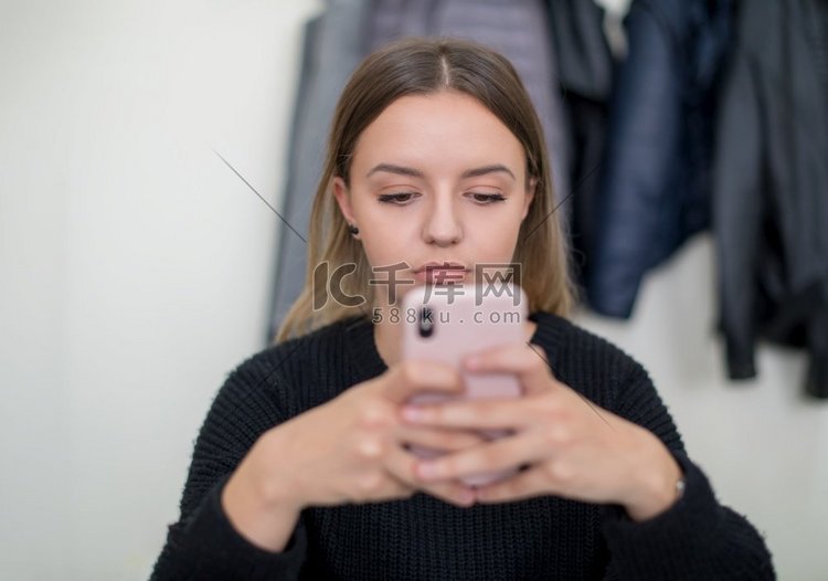 一名年轻的女学生在教室休息时使用手机高清摄影大图-千库网