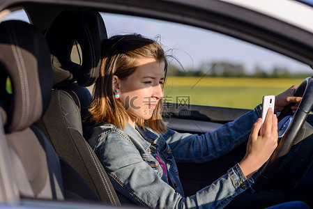 Young female driver reading a text message高清摄影大图-千库网