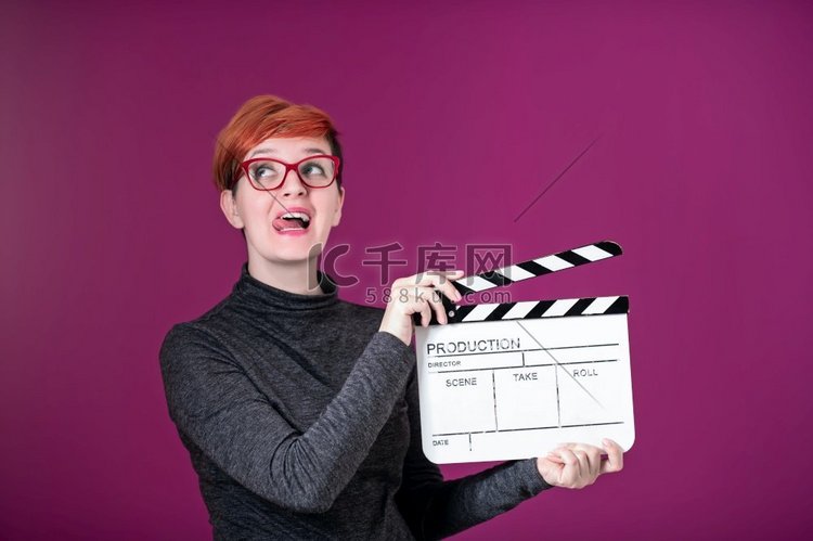 红头发的妇女拿着电影billper孤立的粉红色背景电影概念在工作室高清摄影大图-千库网