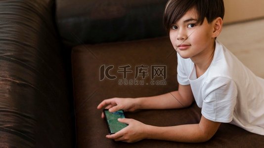 中等拍摄的孩子拿着智能手机高清摄影大图-千库网