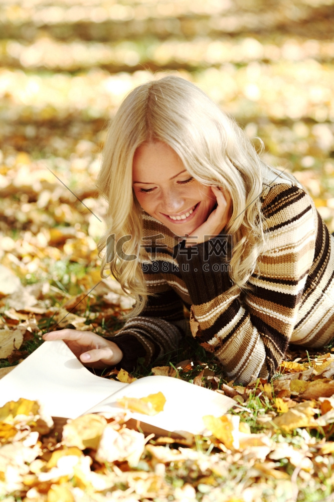 一位女士在秋季公园读了这本书高清摄影大图-千库网