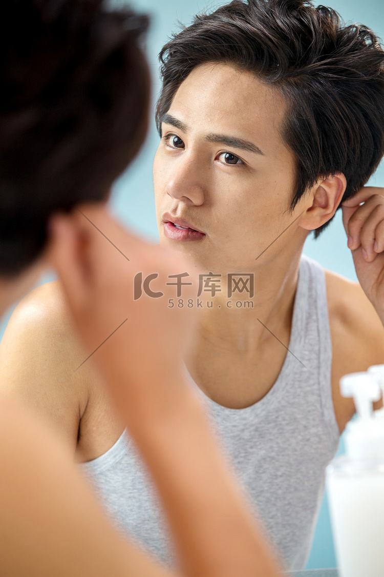照着镜子整理发型的年轻男人高清摄影大图 千库网