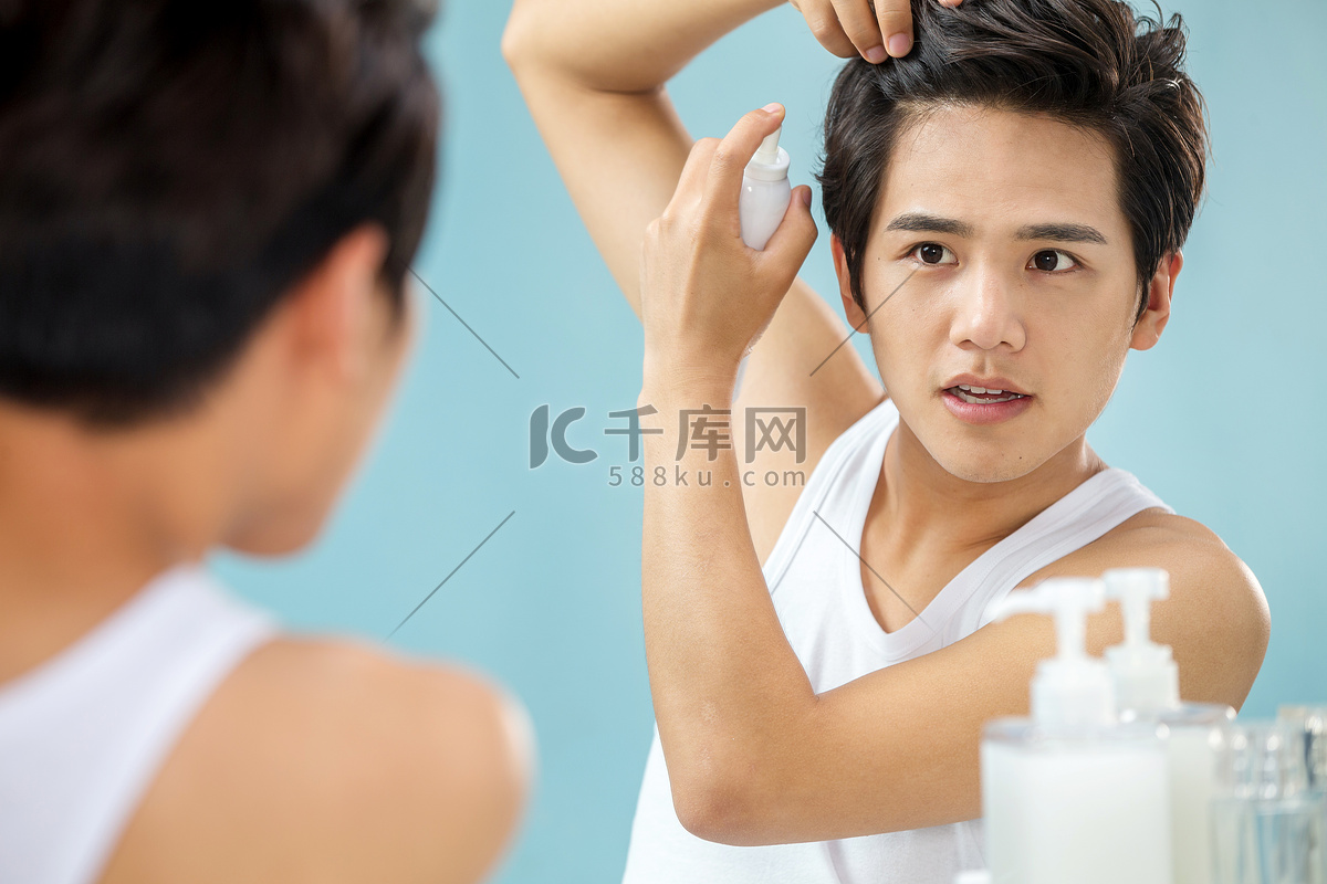 照着镜子给头发喷啫喱的年轻男人高清摄影大图 千库网