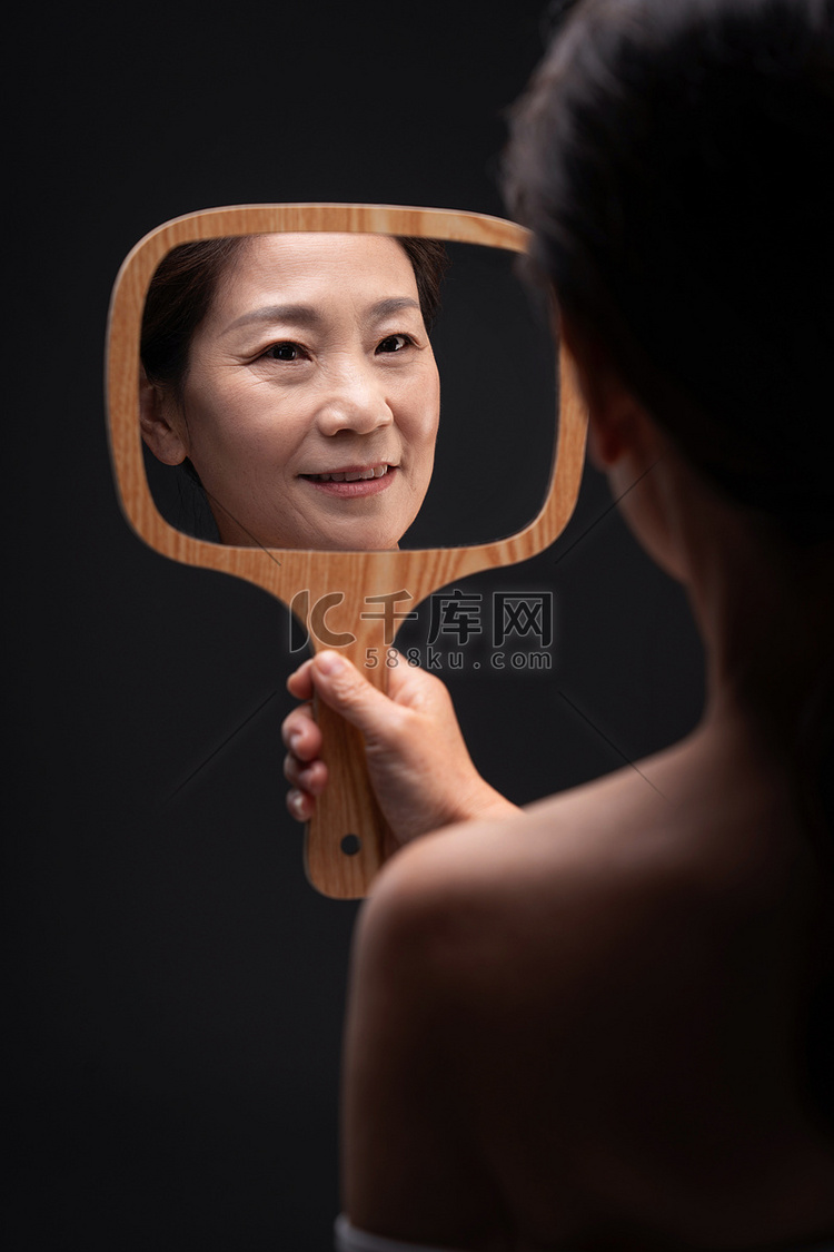 拿着镜子照的中年女人高清摄影大图-千库网