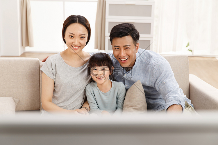 幸福的一家三口在客厅看电视高清摄影大图-千库网