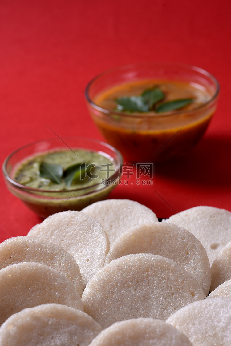 Idli 与 Sambar 和椰子酸辣酱在红色背景上，印度菜：南印度最喜欢的食物 rava idli 或 semolina idly 或 ...