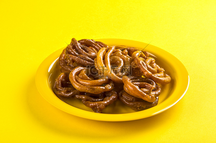 黄色背景中的印度甜 jalebi、印度甜点 jalebi 或 imarti 或 imarati 或 jilbi高清摄影大图-千库网