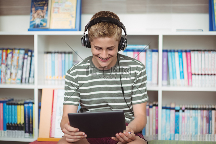 在图书馆使用数字平板电脑时快乐的小学生听音乐高清摄影大图-千库网