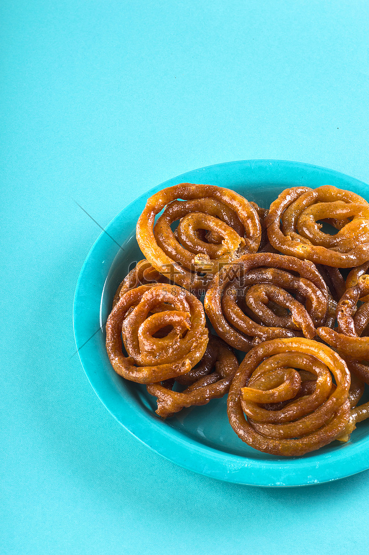 蓝色背景中的印度甜 jalebi、印度甜点 jalebi 或 imarti 或 imarati 或 jilbi高清摄影大图-千库网