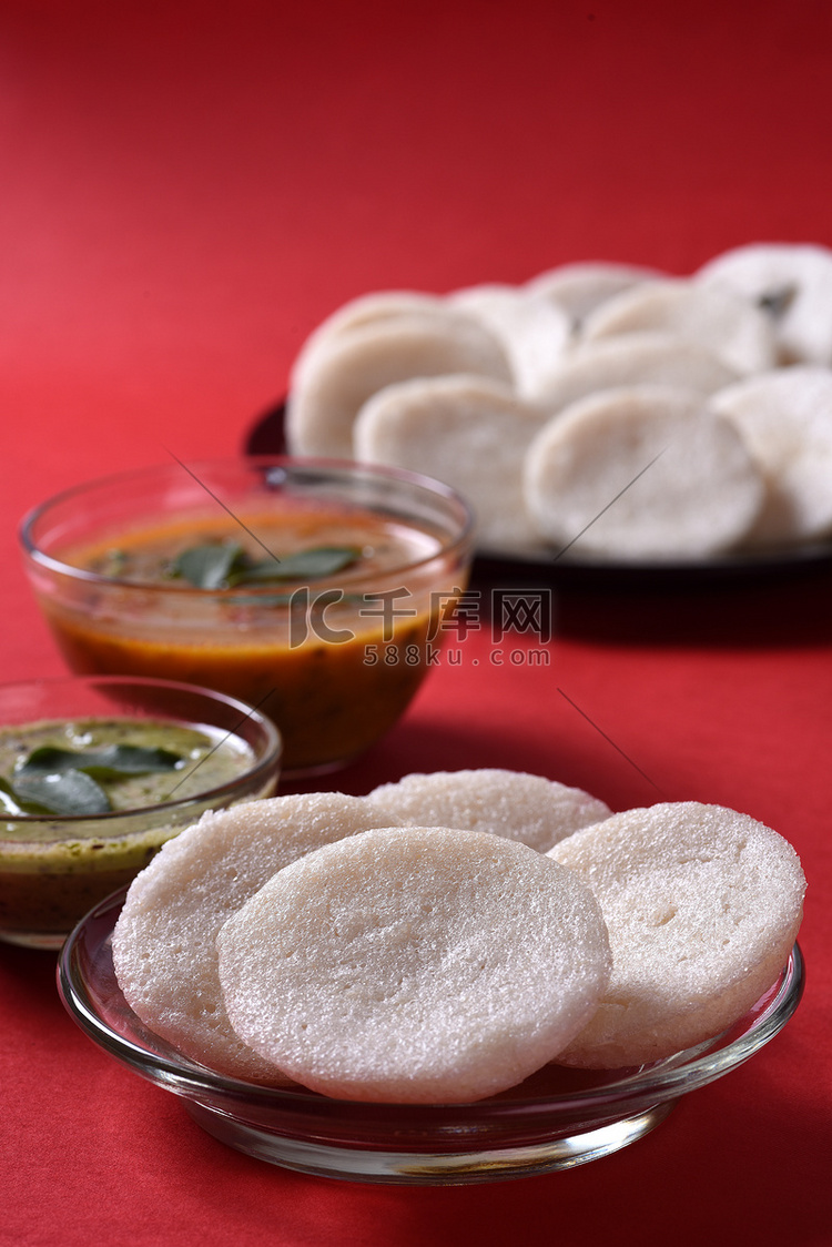 Idli 与 Sambar 和椰子酸辣酱在红色背景上，印度菜：南印度最喜欢的食物 rava idli 或 semolina idly 或 ...