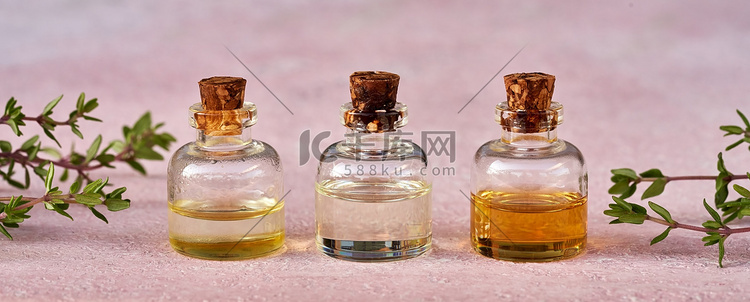 淡粉色背景中带有新鲜百里香树枝的精油瓶高清摄影大图-千库网