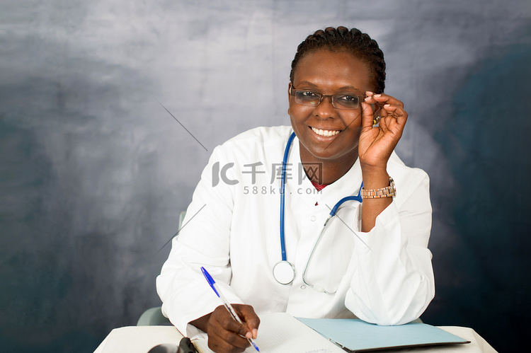 坐在办公室的年轻微笑的女性医生高清摄影大图-千库网