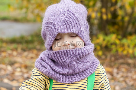 一个戴着紫色针织帽子和围巾的孩子。高清摄影大图-千库网