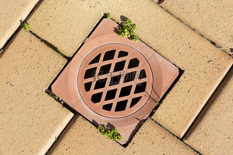 插入棕色铺路石的雨水排水管盖高清摄影大图-千库网