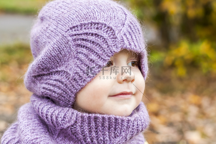 一个戴着紫色针织帽和围巾的孩子。高清摄影大图-千库网