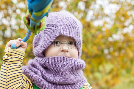 一个戴着紫色针织帽子和围巾的孩子。高清摄影大图-千库网