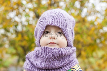 一个戴着紫色针织帽子和围巾的孩子。高清摄影大图-千库网