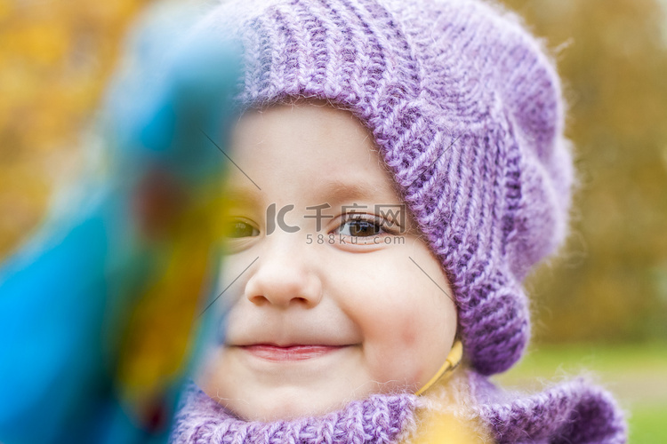 一个戴着紫色针织帽和围巾的孩子。高清摄影大图-千库网