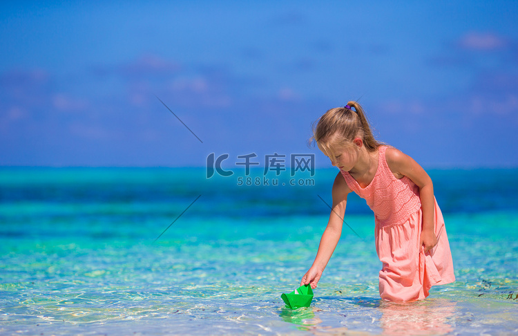 可爱的小女孩在绿松石海中玩折纸船高清摄影大图-千库网