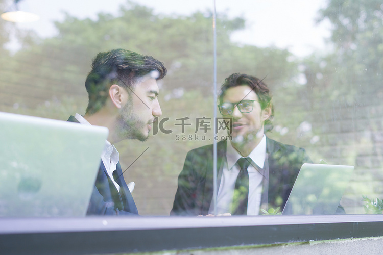 两个年轻的商人使用笔记本电脑一起在办公室工作。高清摄影大图-千库网